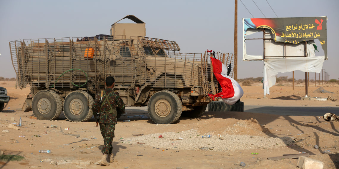 A pro-government Yemeni soldier walks past an armored military vehicle ...